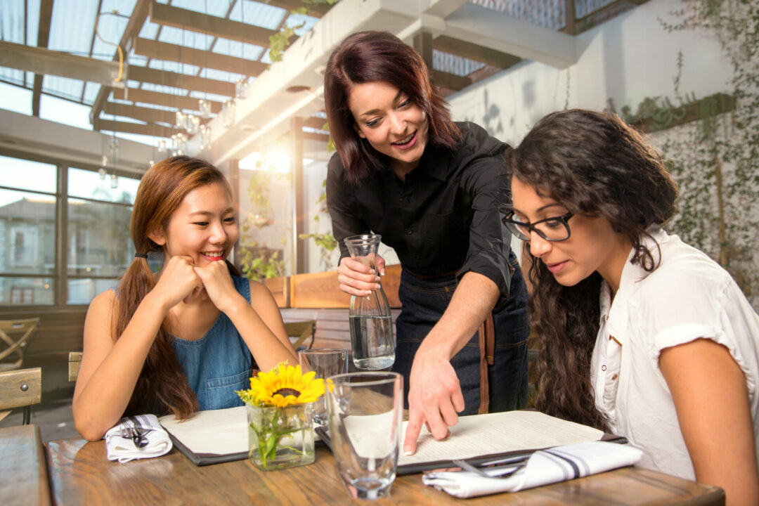 Server waiter pointing to menu for patron customer helping at table ...